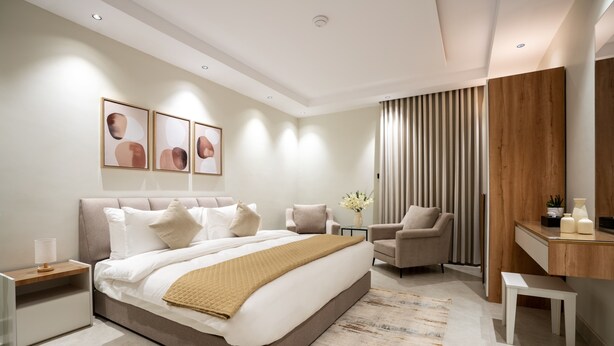 Quarto moderno com cama grande, mesas de cabeceira, escrivaninha e uma cadeira.