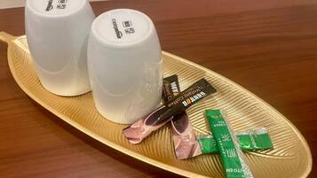 Duas chávenas brancas sobre um prato dourado com alguns pacotes de comida.