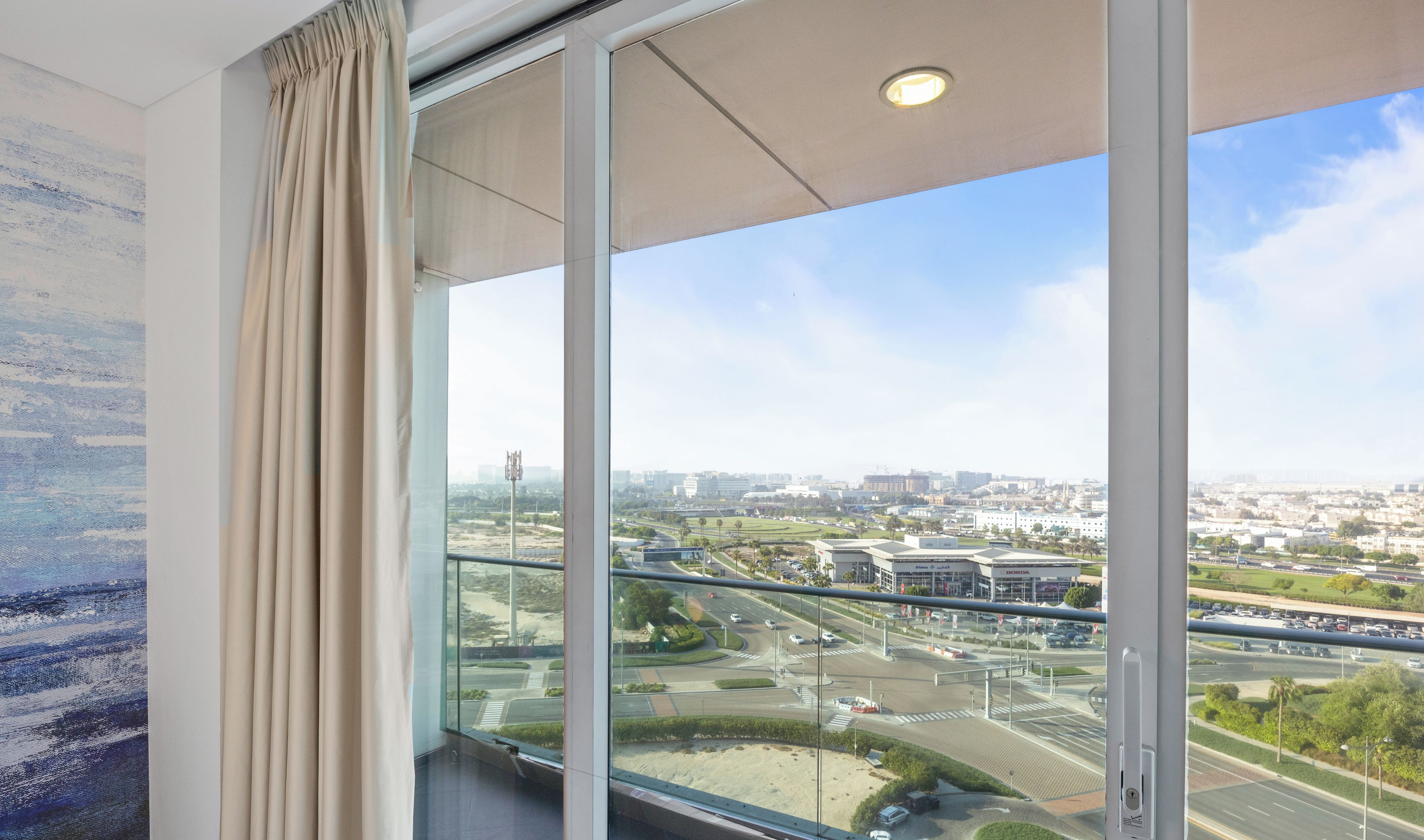 Quarto de hotel moderno com uma varanda grande, vista para a cidade e janela com cortinas.
