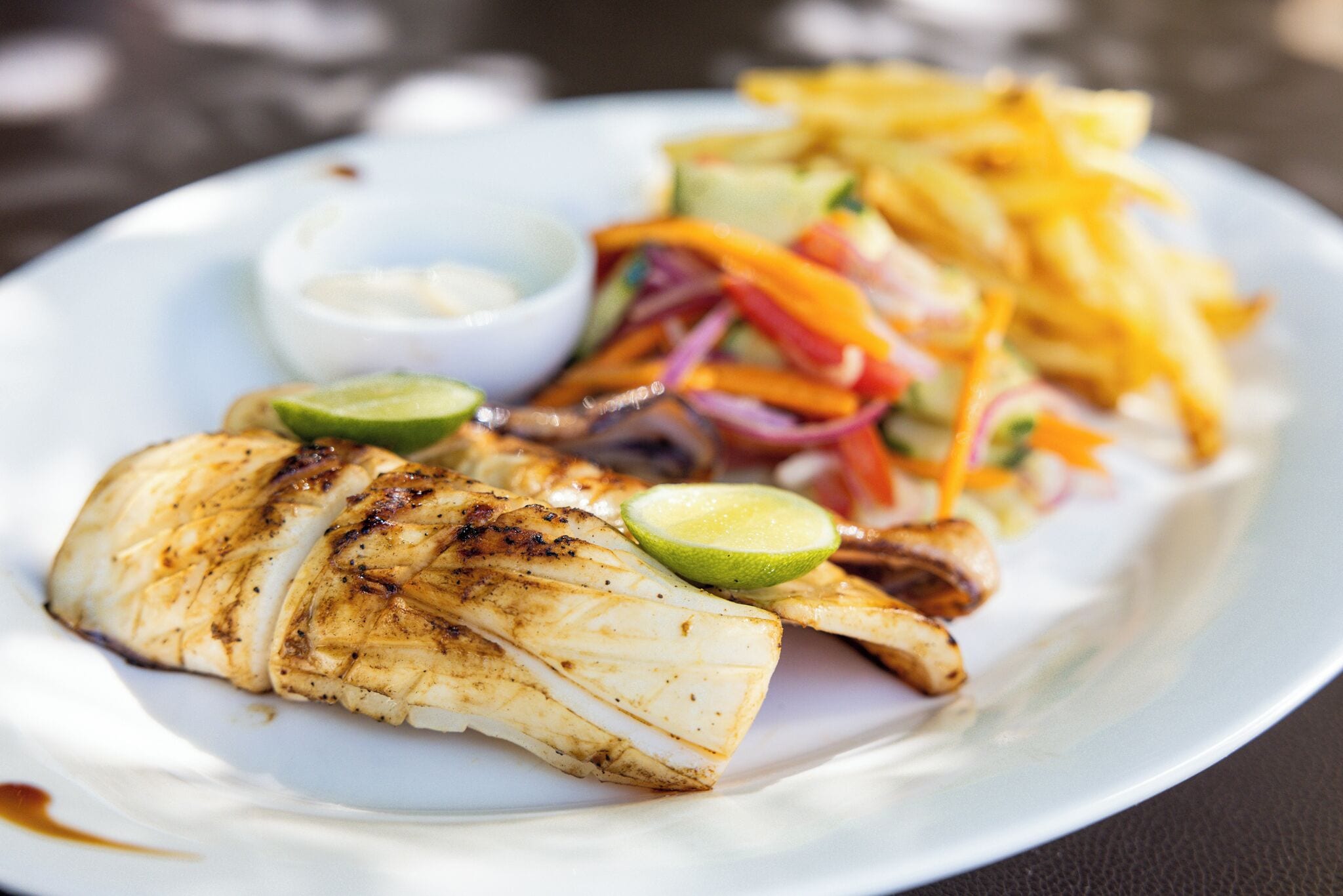 Um prato de peixe grelhado acompanhado de legumes e batatas fritas.