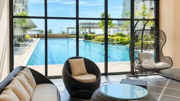Uma área de estar moderna com mobiliário de vime, uma mesa de vidro e vista para uma piscina.