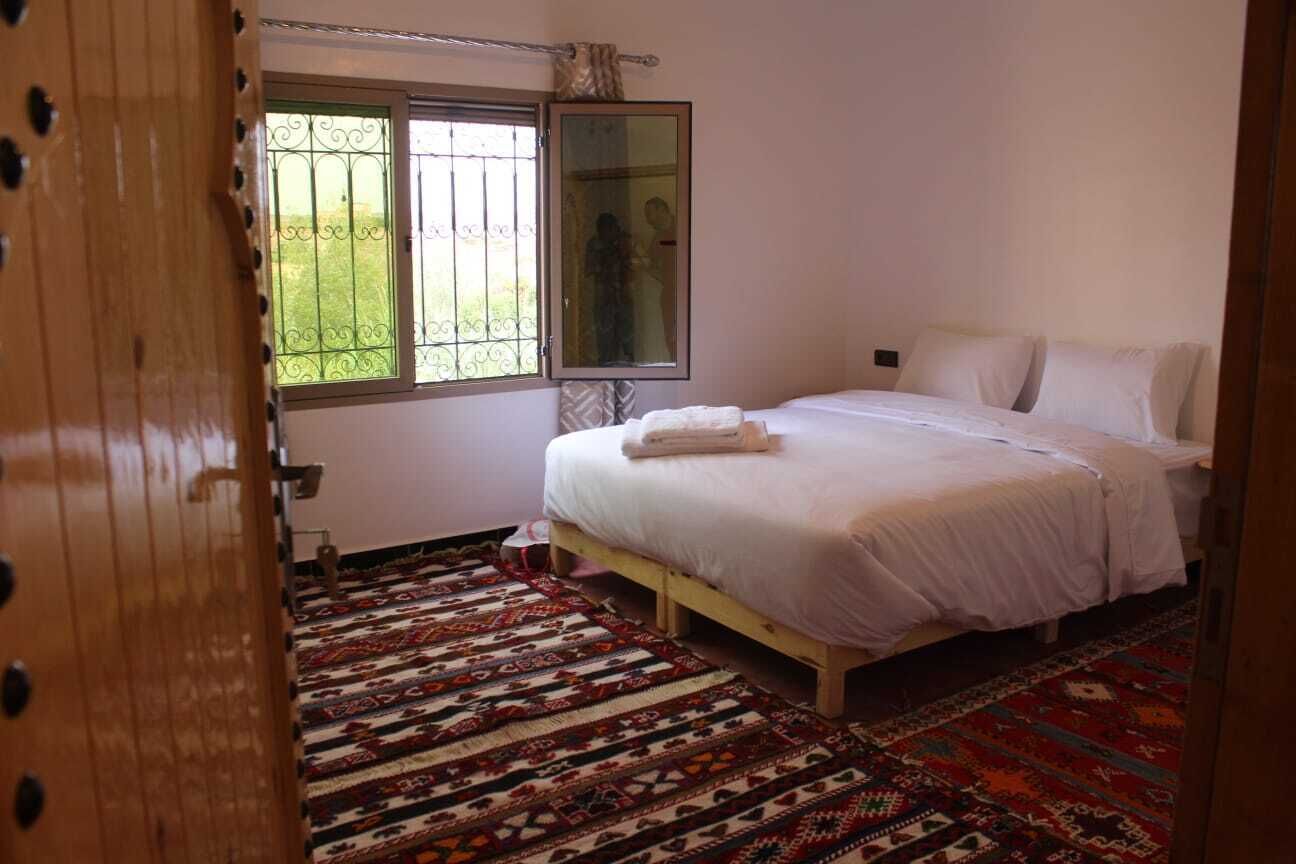 Quarto com cama, janela com grades, espelho e tapete estampado.