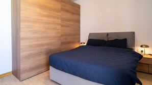 Quarto moderno com cama grande, guarda-roupa de madeira e abajures.