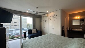 Quarto moderno com cama, ventilador de teto, sofá e uma janela grande.