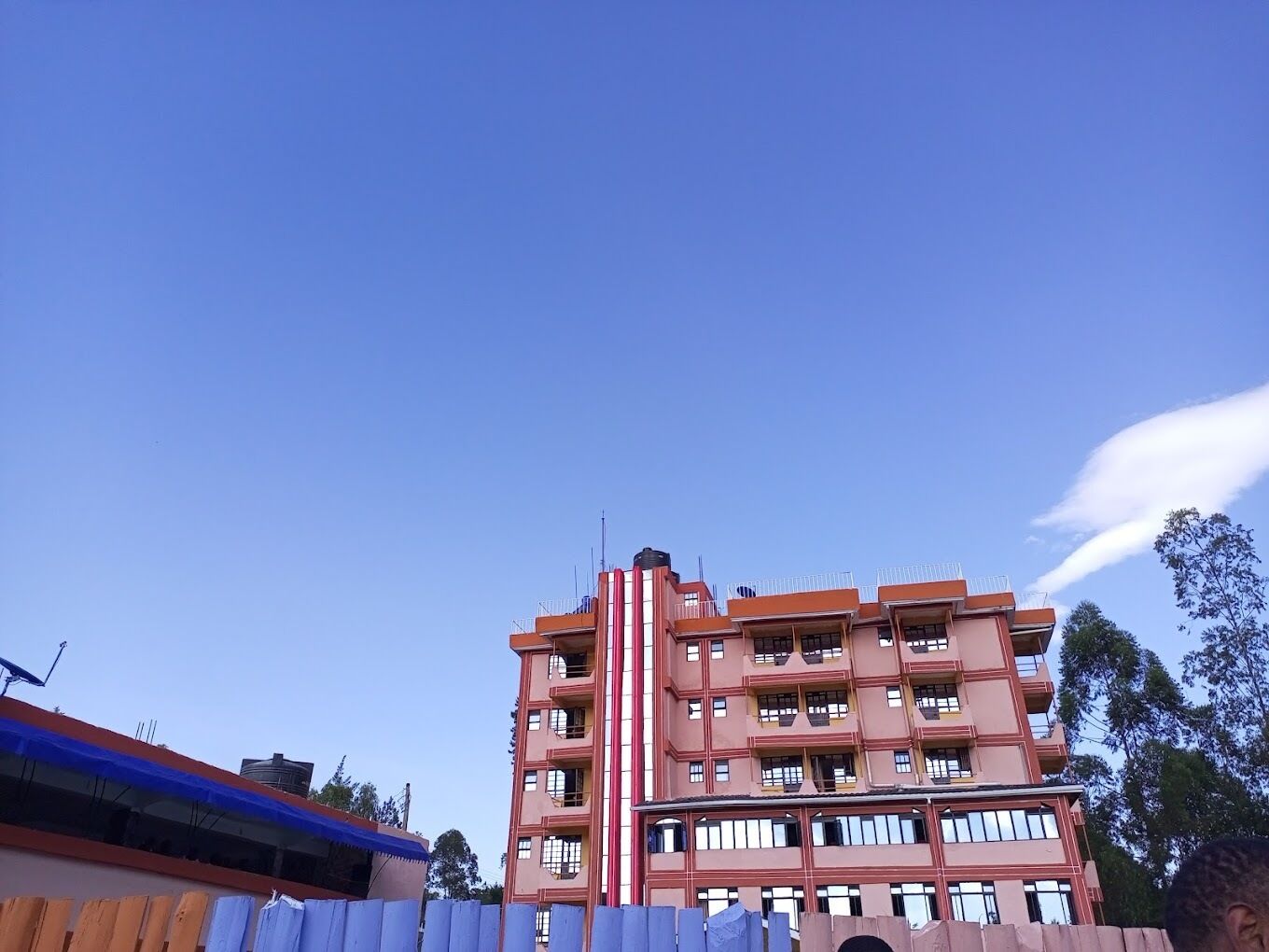 Um edifício de vários andares com uma estrutura vertical central, varandas e um telhado plano.