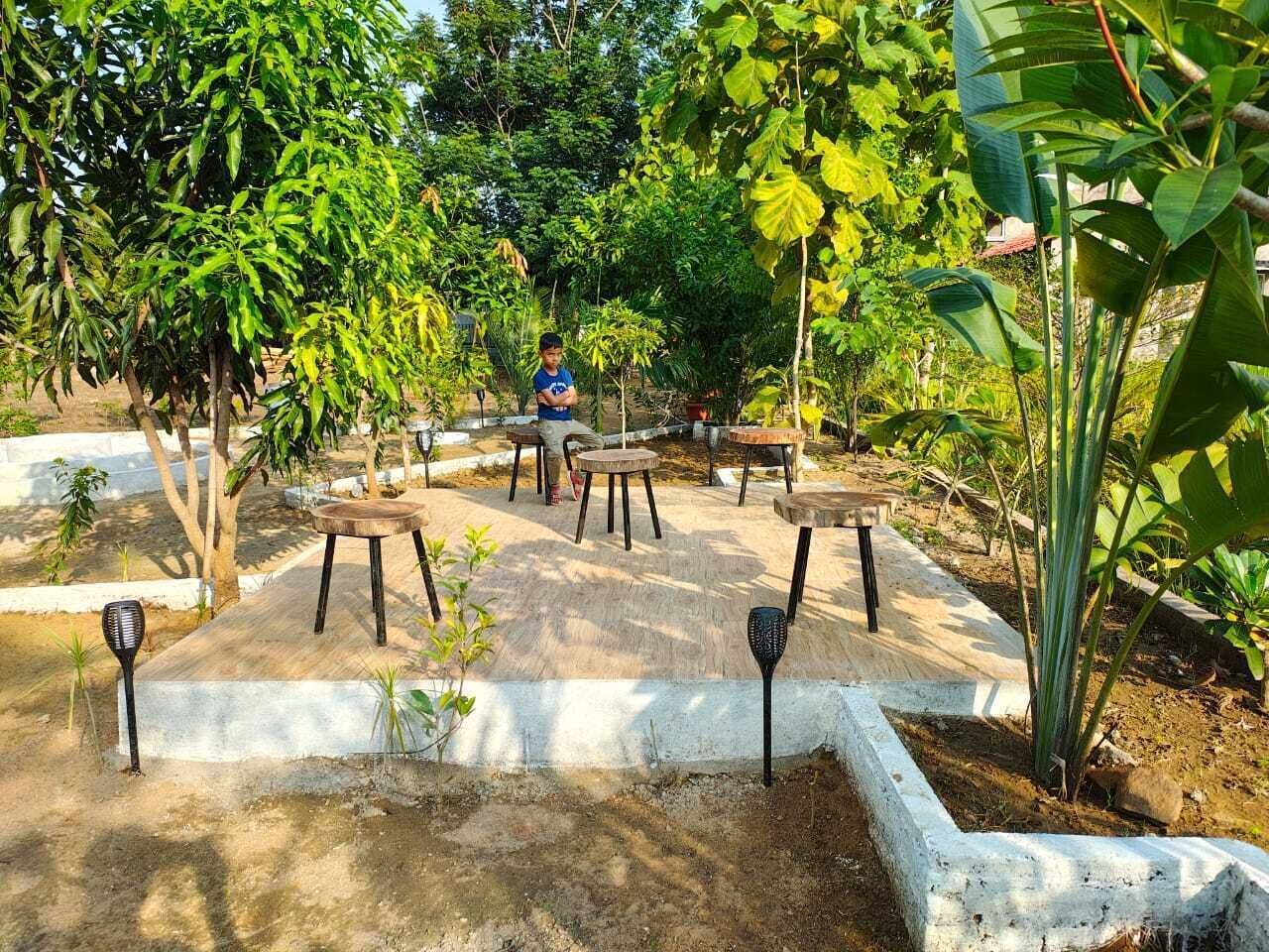 Uma área externa com mesas e cadeiras, rodeada por vegetação e árvores.