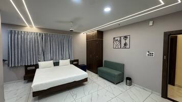 Quarto moderno com uma cama grande, um sofá verde, um guarda-roupa e iluminação embutida no teto.