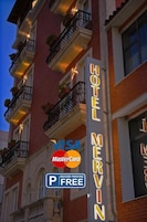 Placa de hotel com a inscrição 'HOTEL MERVIN' e 'ESTACIONAMENTO COBERTO GRÁTIS'.