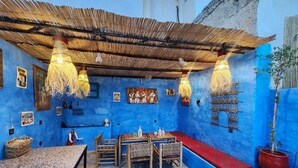 Um quarto com parede azul, mesa de madeira, banco e luminárias pendentes.