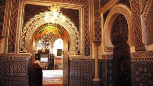 Interior ornamentado com trabalhos em azulejos detalhados, um candelabro e um arco grande.