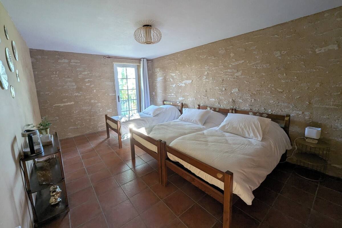 Quarto com uma cama grande, mesa de cabeceira, cadeira, janela com cortinas e luminária no teto.