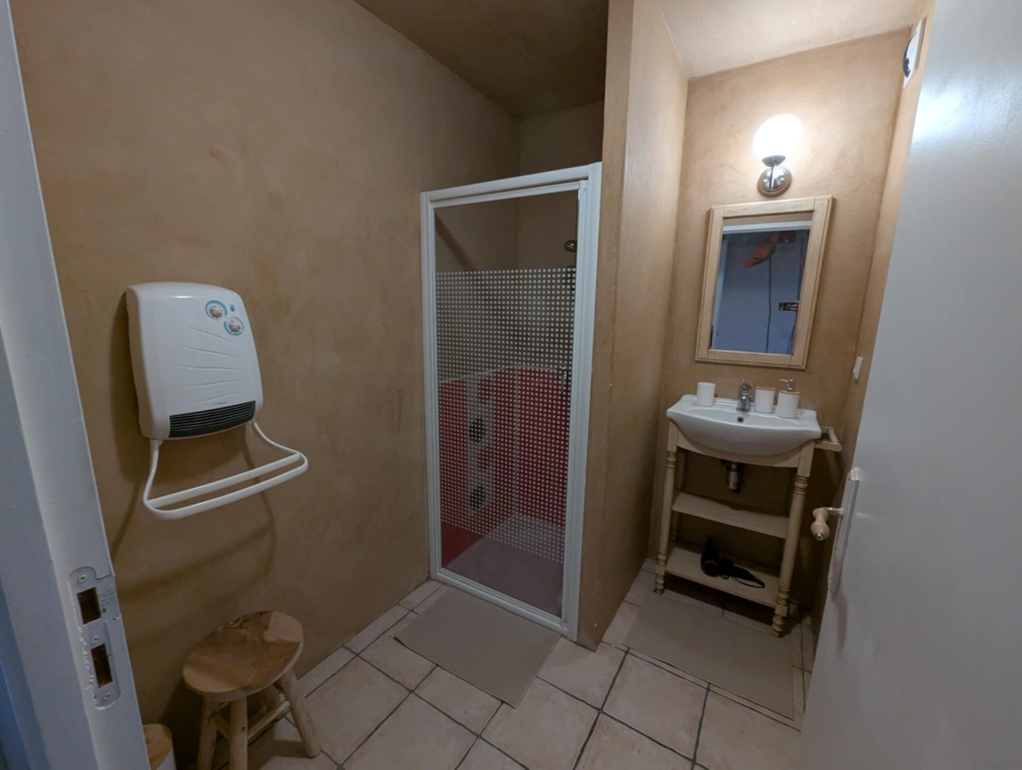 Casa de banho pequena com chuveiro, lavatório e secador de mãos.