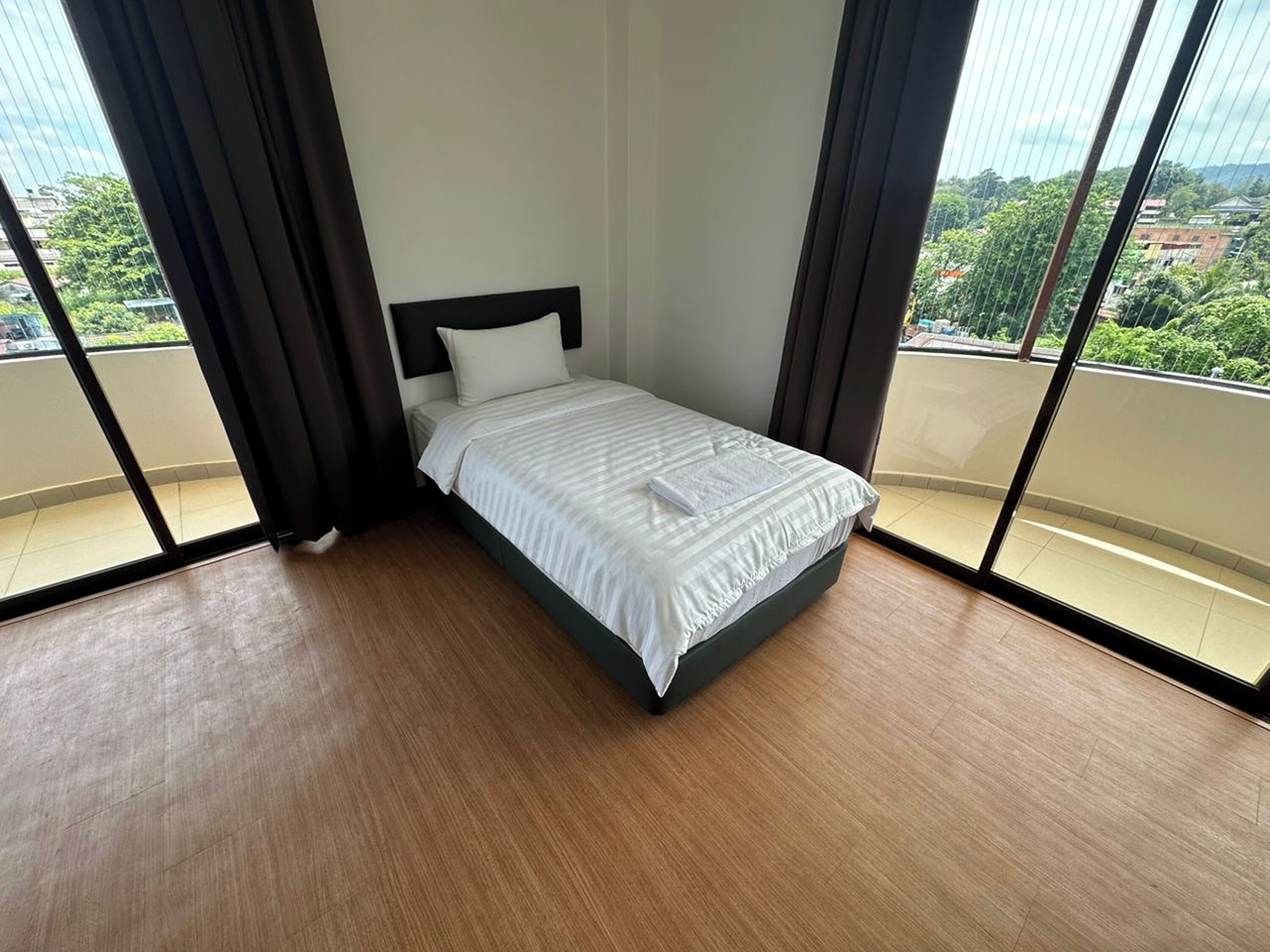 Quarto com cama, janelas amplas e vista da cidade.