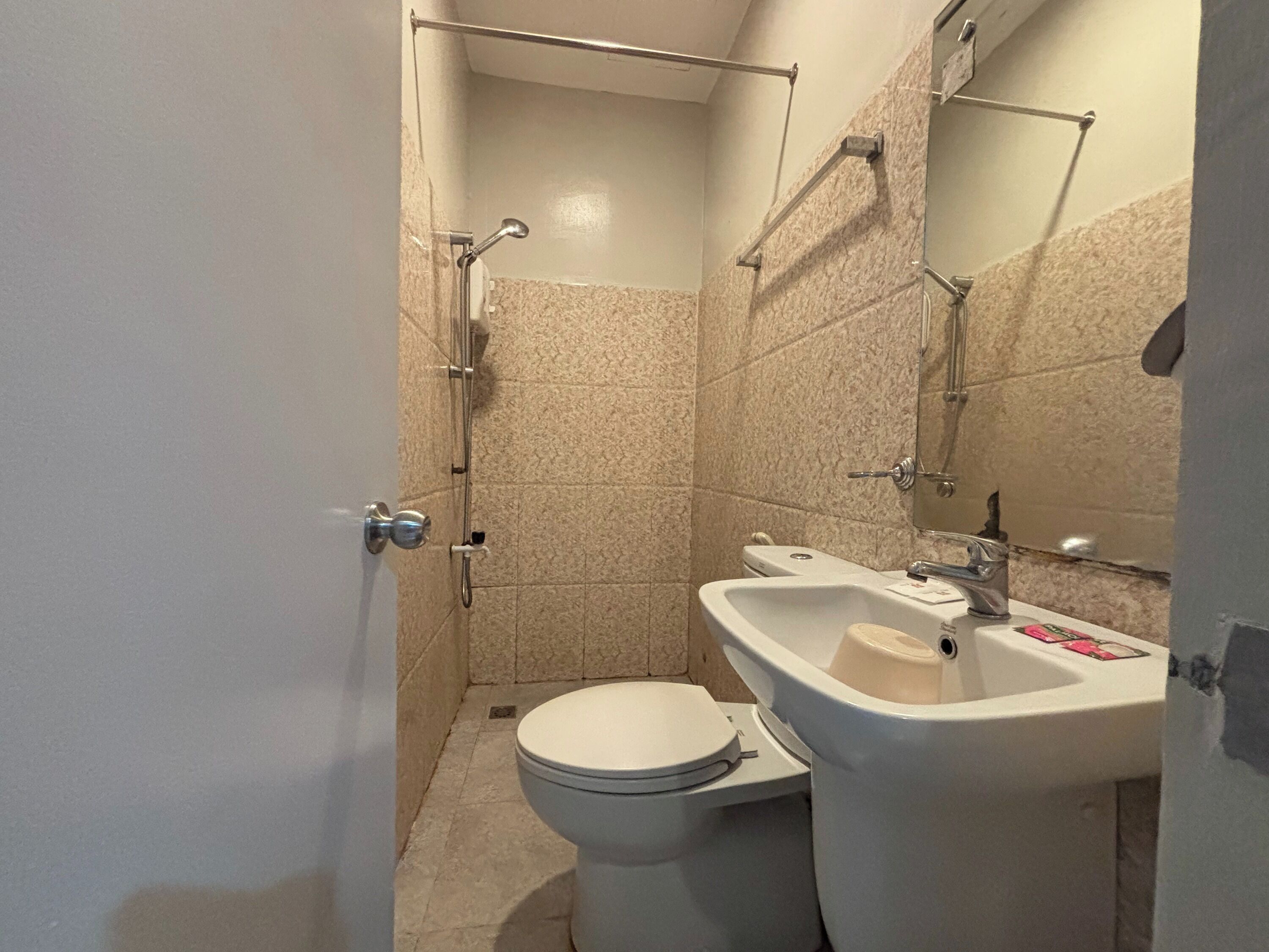 Uma casa de banho pequena com sanita, lavatório e chuveiro.