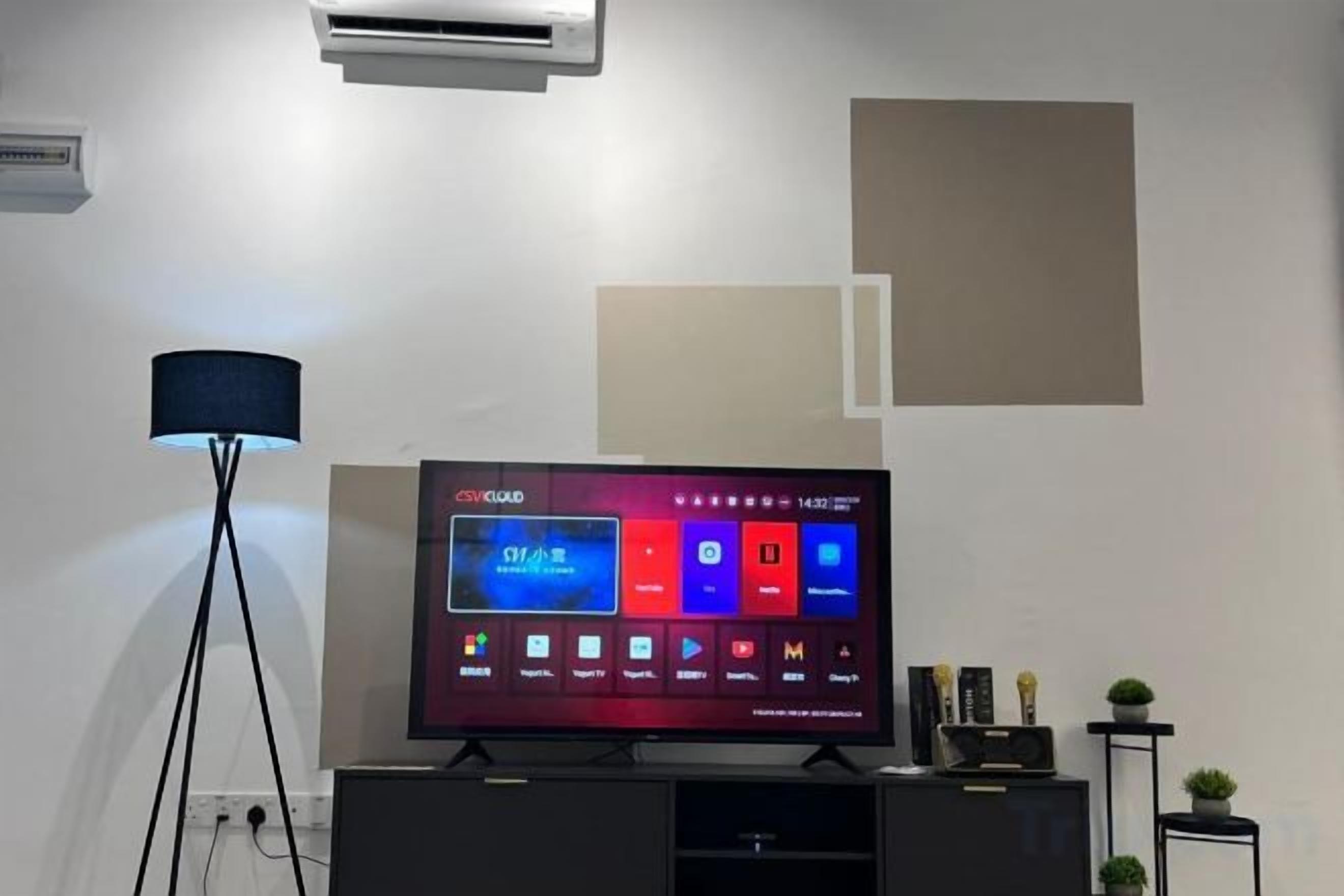 Televisão de tela plana na parede, exibindo aplicativos e um relógio em sua interface digital.