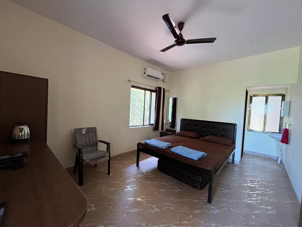 Quarto com cama, cadeira, escrivaninha e ventoinha no teto.