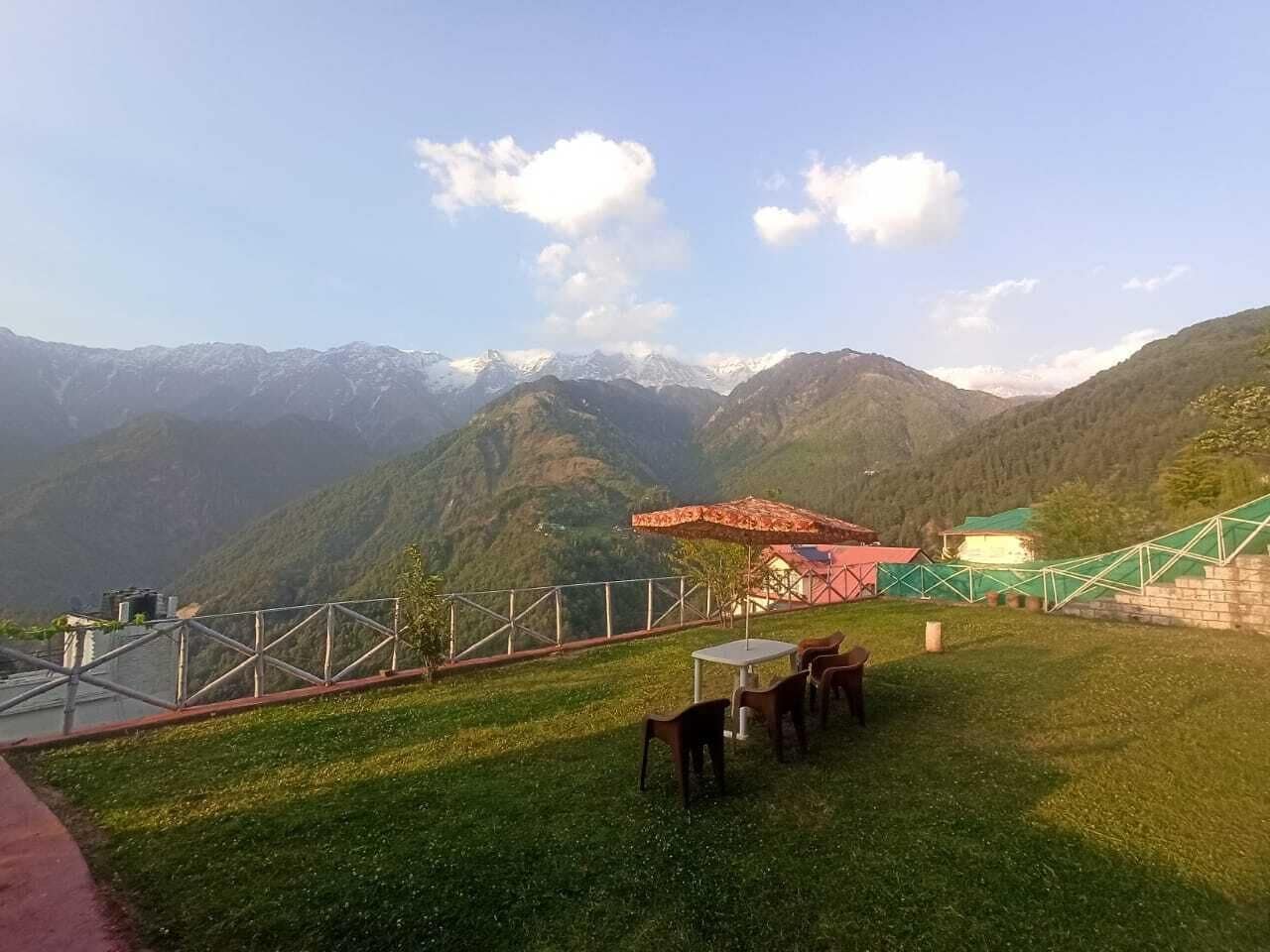 Um terraço com mesa e cadeiras, com vista para uma paisagem montanhosa.