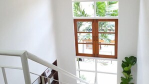 Escadaria com corrimão branco e vista para uma porta de madeira com painéis de vidro.