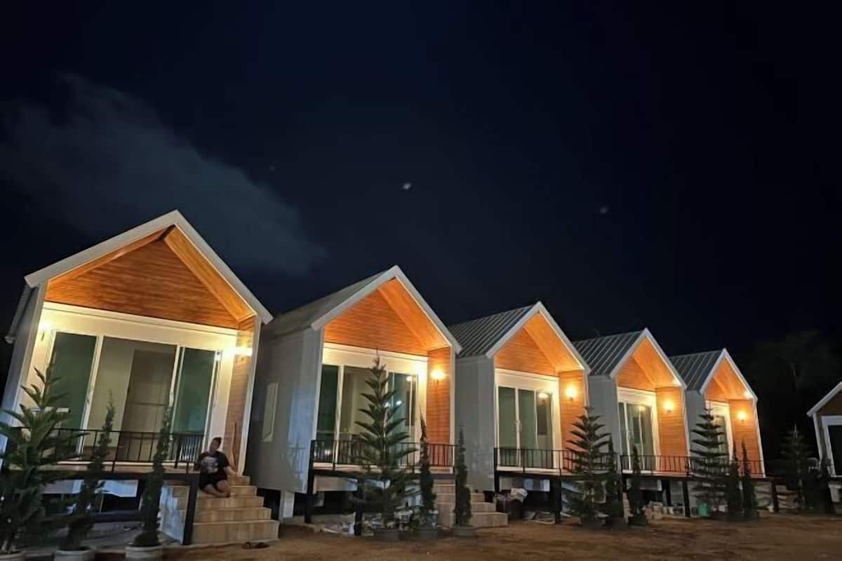 Uma fileira de cabanas de madeira com janelas amplas e um alpendre coberto.