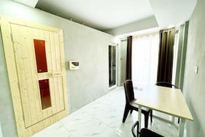 Um quarto com porta de madeira, mesa de jantar e cadeiras.