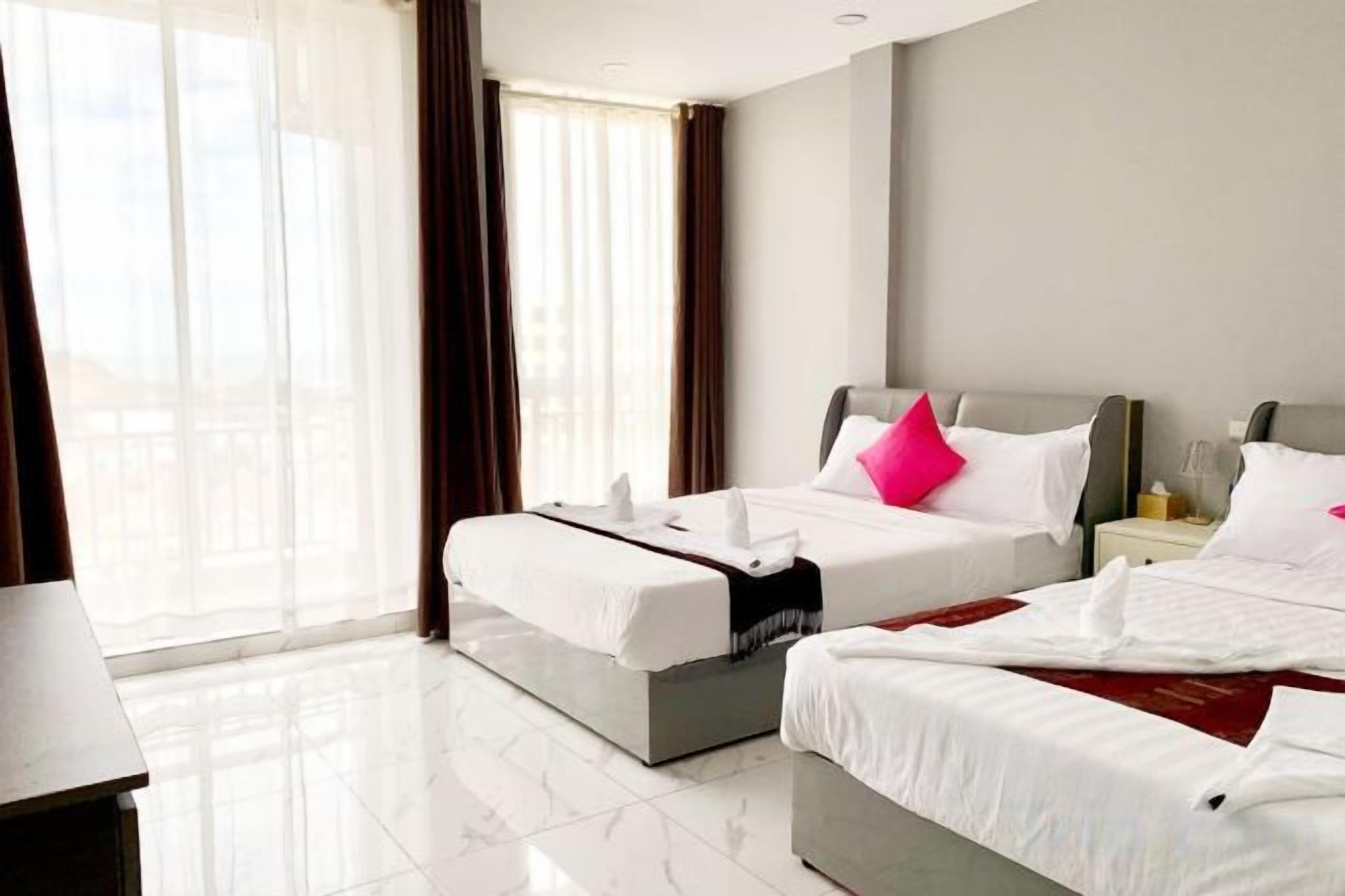 Quarto de hotel com duas camas, uma janela grande e vista para a cidade.