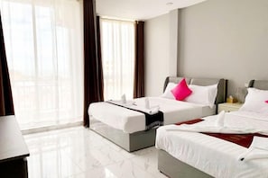 Quarto de hotel com duas camas, uma janela grande e vista para a cidade.