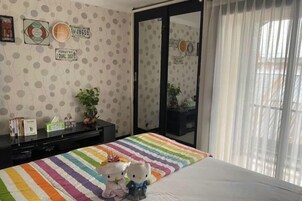 Quarto com colcha listrada, um espelho e uma planta sobre um penteadeira.