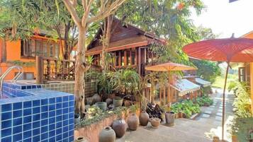 Pátio com piscina, plantas em vasos e estrutura de madeira.