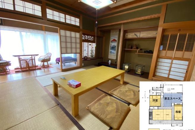 Um quarto japonês tradicional com tatames, uma mesa de madeira baixa e portas deslizantes.