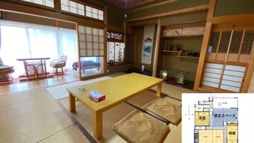 Um quarto japonês tradicional com tatames, uma mesa de madeira baixa e portas deslizantes.