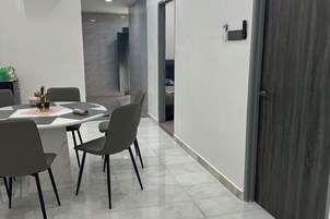 Uma área de jantar moderna com uma mesa redonda, quatro cadeiras e um vaso com talheres.