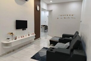 Uma sala de estar moderna com uma TV de tela plana, um sofá, uma mesa de centro e uma parede decorativa com caracteres chineses.