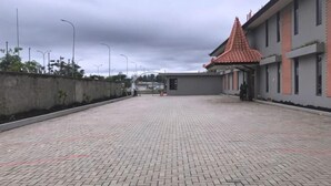 Um pátio pavimentado com um edifício com telhado de telhas vermelhas.