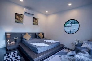 Quarto moderno com cama grande, mesas de cabeceira e obras de arte nas paredes.