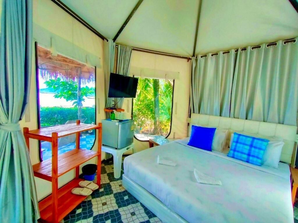 Quarto tipo tenda com uma cama, uma televisão e uma pequena escrivaninha.