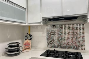 Cozinha com armários brancos, fogão a gás e painel de azulejos.