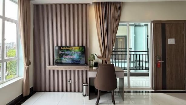Quarto de hotel moderno com televisão, escrivaninha, cadeira e varanda com vista.