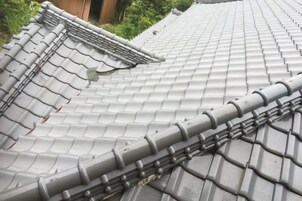 Telhado com telhas cinzas e calha de metal.