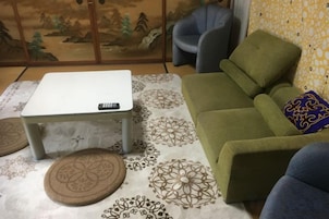 Quarto com sofá, mesa pequena e tapete estampado.