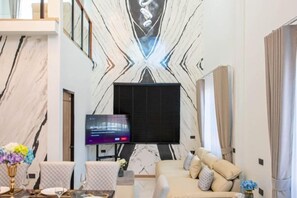 Uma sala de estar moderna com televisão de tela plana, um sofá e um espaço de jantar com mesa e cadeiras.