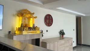 Uma área de recepção com uma mesa, um objeto decorativo na parede e uma placa com caracteres chineses.