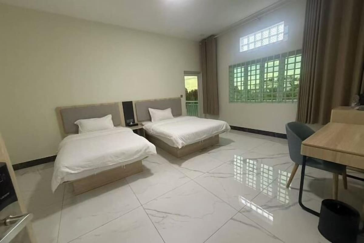 Quarto de hotel com duas camas, uma mesa e uma cadeira.