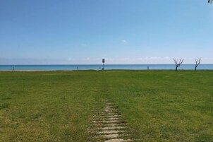 Um campo gramado com céu limpo e vista distante do oceano.