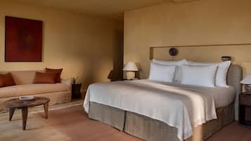 Quarto com cama, sofá, mesa pequena e abajur.