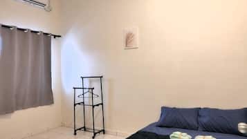 Quarto com cama, porta-toalhas e ar-condicionado na parede.