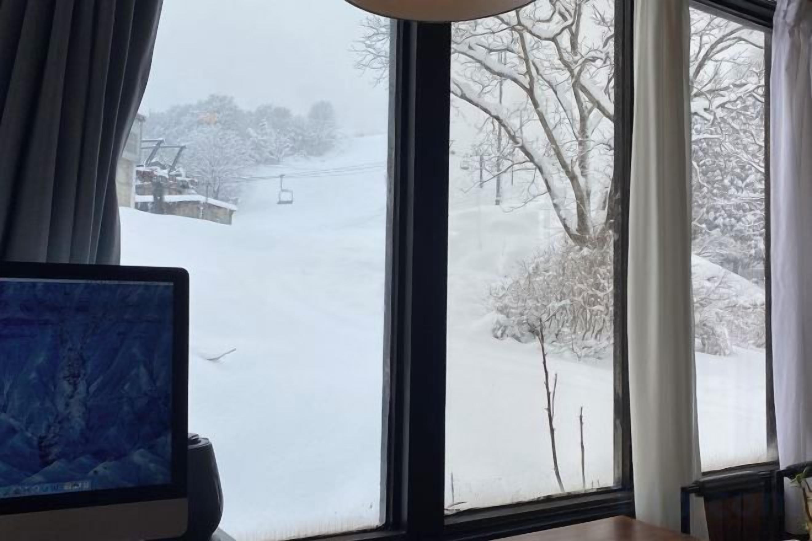 Quarto com vista para uma paisagem nevada pela janela.