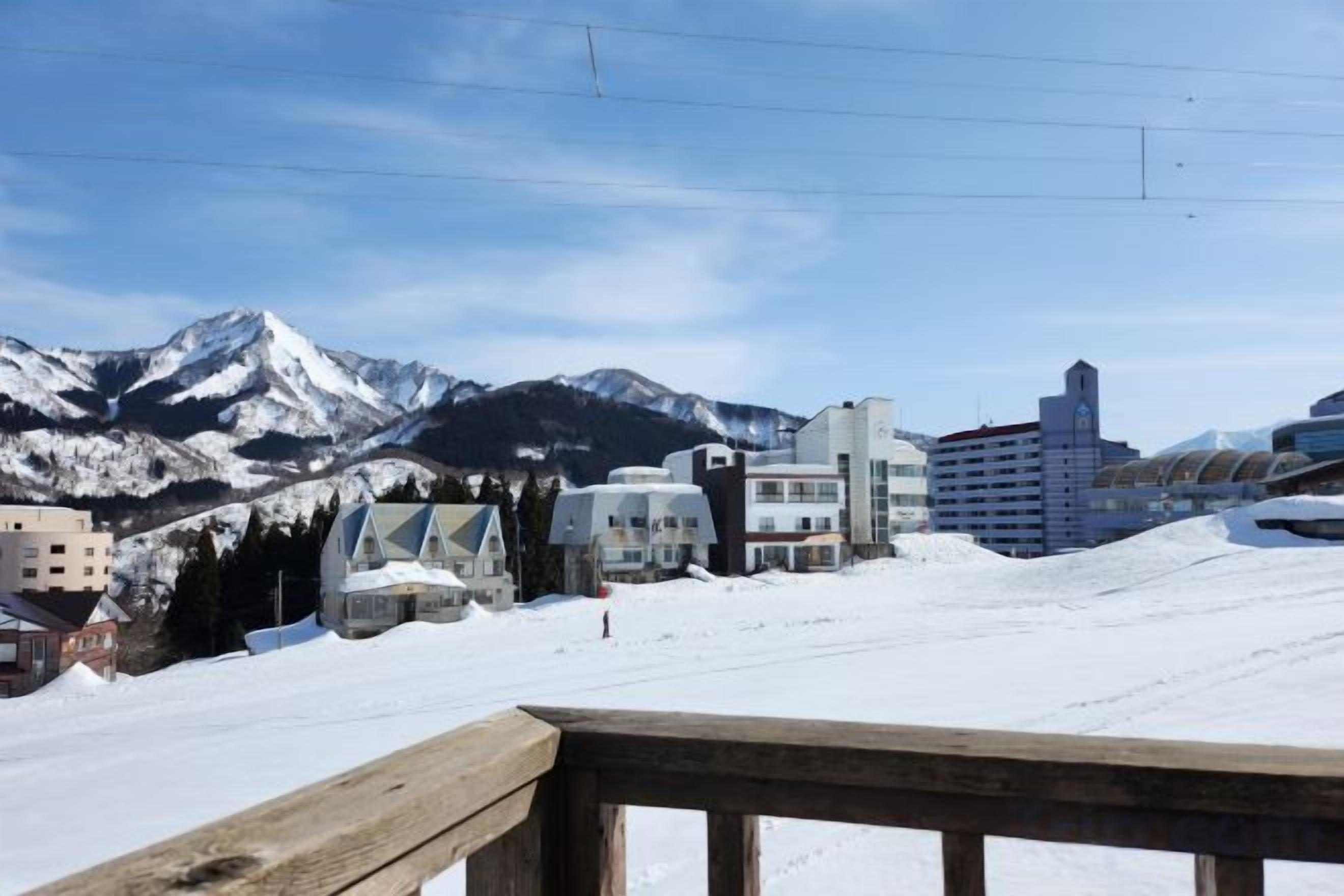 Pista de esqui coberta de neve, com edifícios ao fundo, incluindo um hotel e um teleférico.