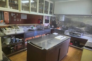 Uma cozinha comercial com eletrodomésticos de aço inoxidável, uma ilha central ampla e uma janela com vista para a cozinha.