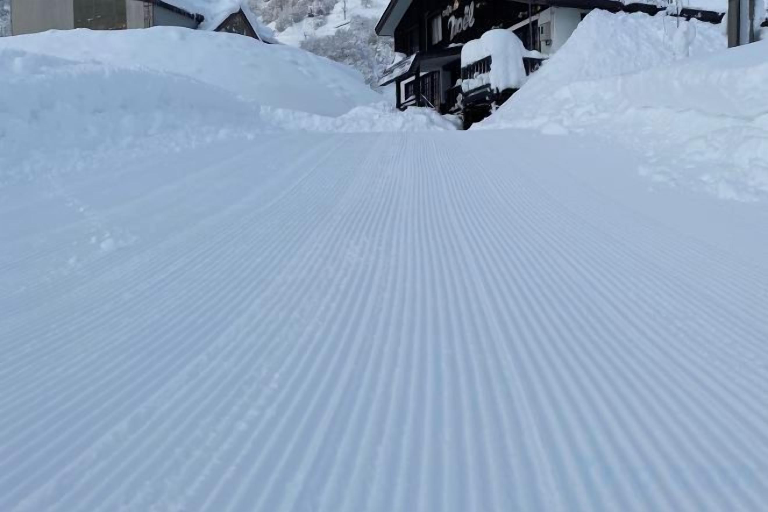 Caminho coberto de neve que leva a um edifício com telhado inclinado.