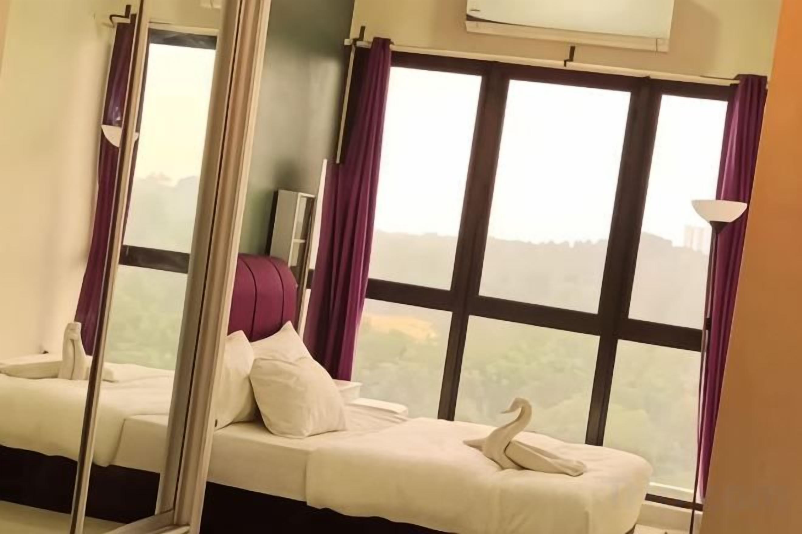 Quarto de hotel com cama, espelho, janela com cortinas e vista para o exterior.